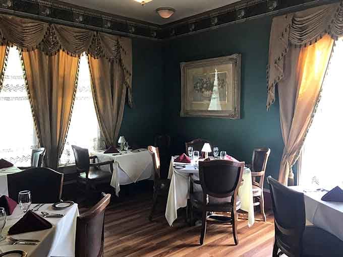 Deep teal walls, golden drapes, and white linens, because some dining rooms simply refuse to be ordinary.