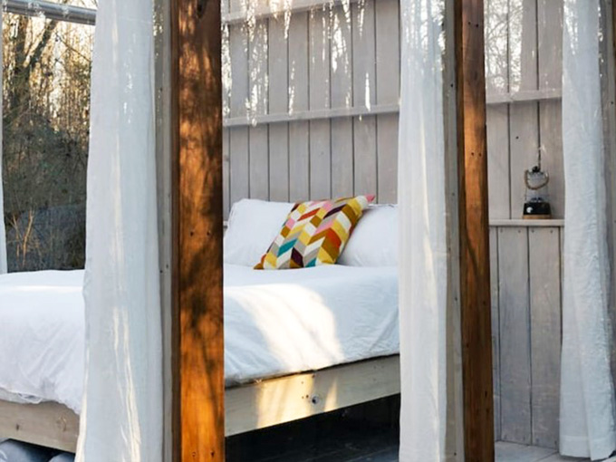 White curtains, crisp linens, and a colorful pillow. This tiny bedroom has more charm than most full-sized hotels.