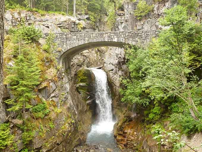 That historic stone bridge isn't just for show, it perfectly frames this elegant cascade beneath Mount Rainier's watchful gaze.