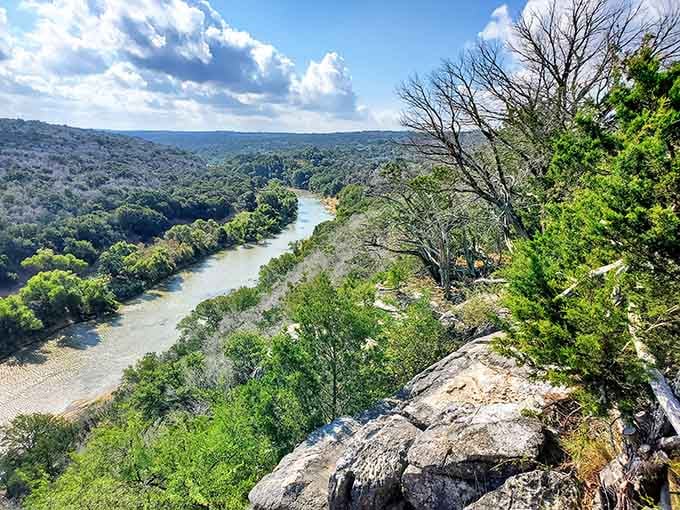 The Colorado River winds through green hills like a silver ribbon, creating a view that makes the climb worthwhile.