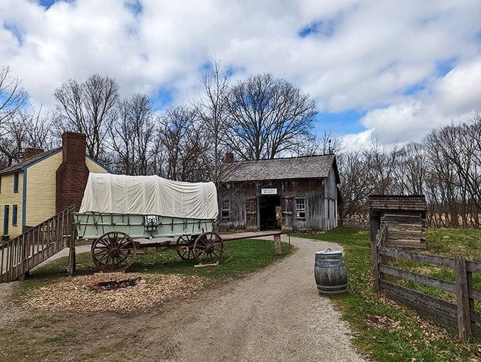 A covered wagon parked outside a weathered barn proves some road trips looked very different back then.