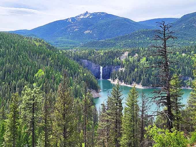 A thundering waterfall crashing into turquoise water, framed by endless green forest and a mountain that means serious business.