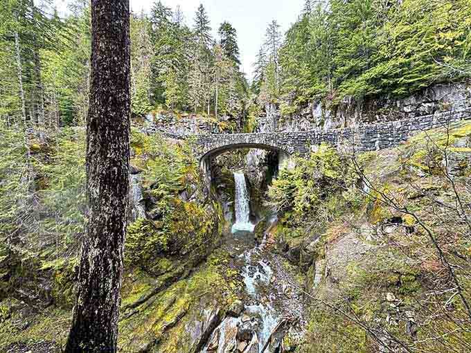 From above, the waterfall tucks beneath the graceful arch, revealing layers of falling water through century-old stonework.