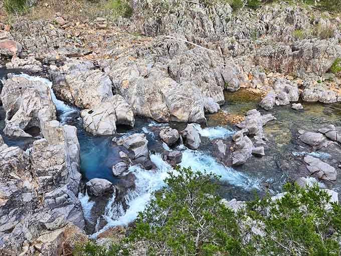 Crystal-clear blue water tumbles between moss-kissed boulders, creating natural pools so inviting you'd forgive yourself for canceling your afternoon plans entirely.