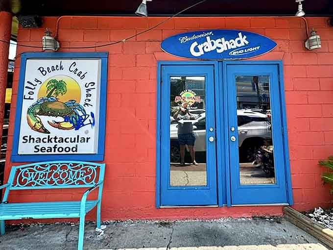 That coral-red wall and cheerful blue bench practically shout "shacktacular seafood" before you even reach the door.