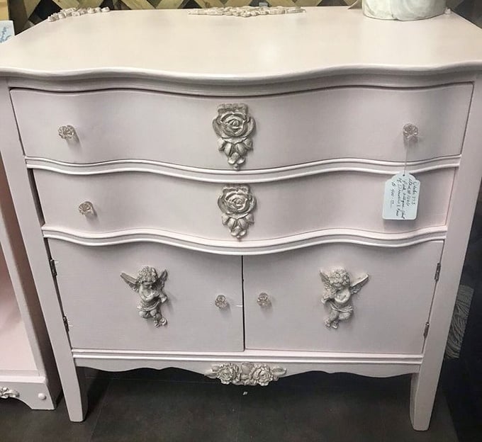 That blush dresser with silver cherubs isn't furniture; it's a conversation piece waiting to happen.