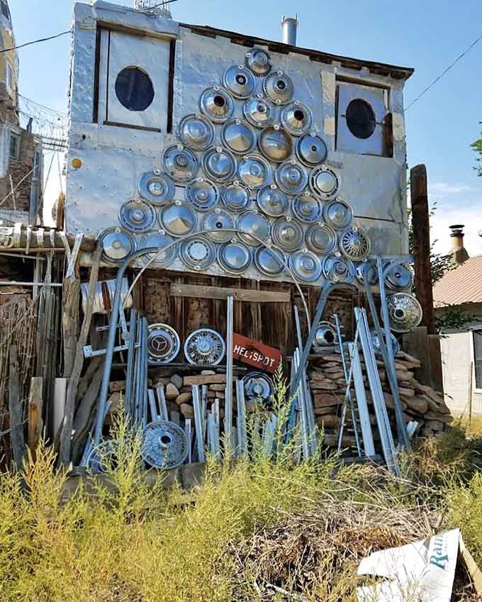 Dozens of hubcaps arranged in a perfect triangle, because why put them on a car when you can build a castle?