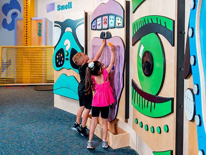 Two curious kids tackle a giant sensory wall, proving that learning about smell and sight is way more fun than any worksheet ever was.