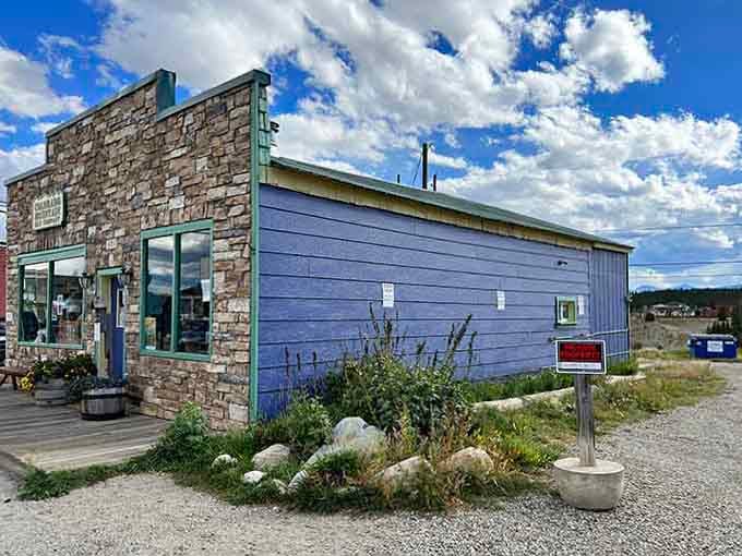 The local country store sits ready to serve, its blue siding a cheerful contrast to the rugged mountain landscape beyond.