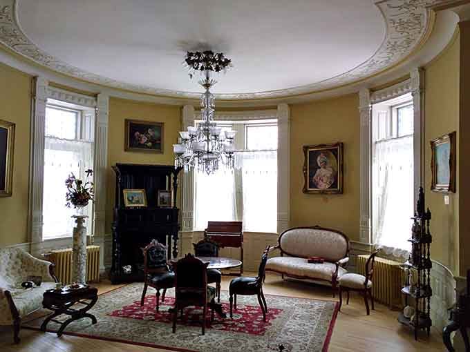 The circular parlor's ornate plasterwork ceiling and crystal chandelier make every other living room feel deeply inadequate.