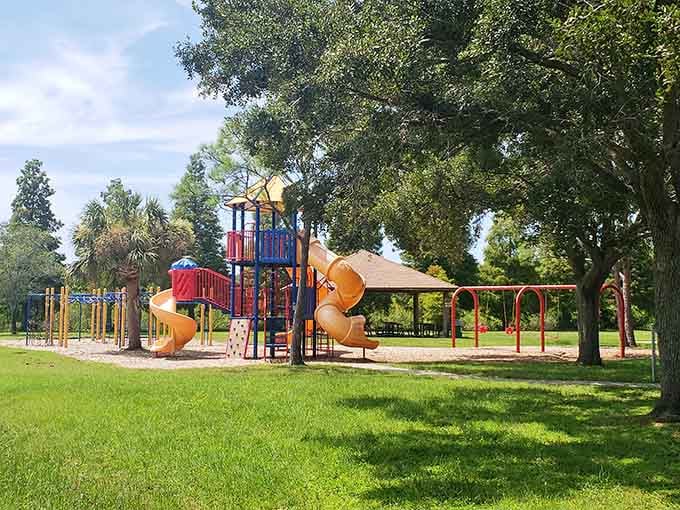 Sheffield Park's colorful playground equipment under shady oaks: where childhood memories are made without the tourist admission fees.