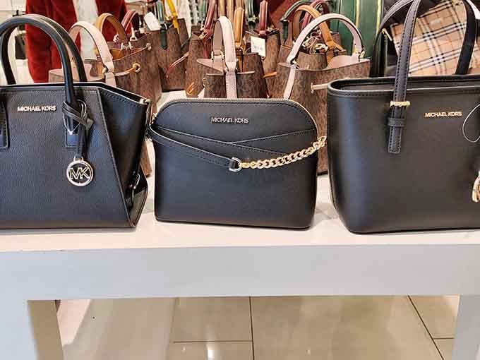 Michael Kors bags lined up like they're posing for a portrait. Sophisticated, sleek, and surprisingly affordable here.