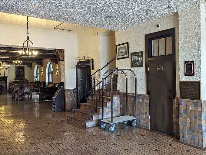 That vintage luggage cart and wrought iron staircase tell you immediately this place has real stories to tell.