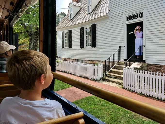 A young explorer watches a costumed interpreter wave from a historic doorway, proof that Fredericksburg's past is very much alive.