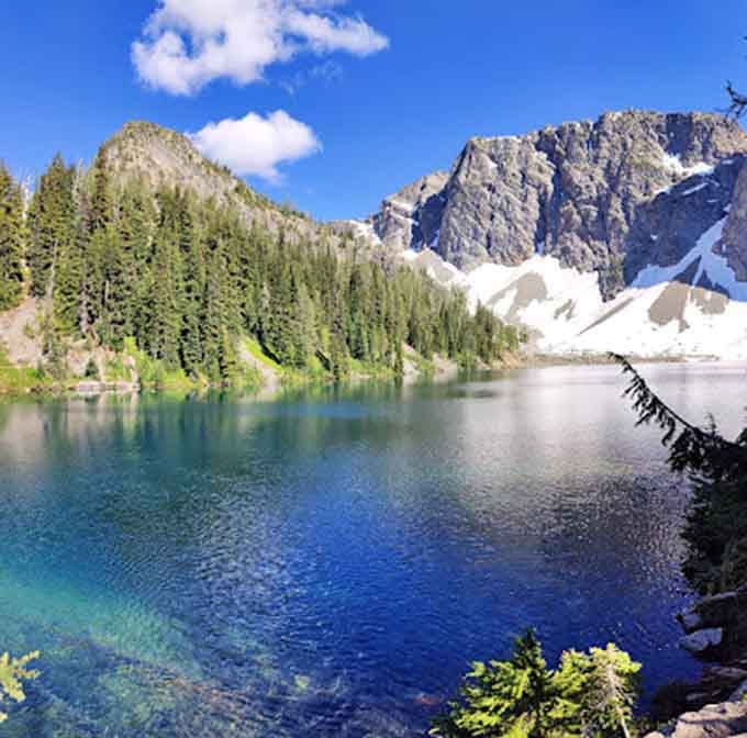Crystal-clear alpine water reflects snow-capped peaks like a mirror that forgot it was supposed to be horizontal.