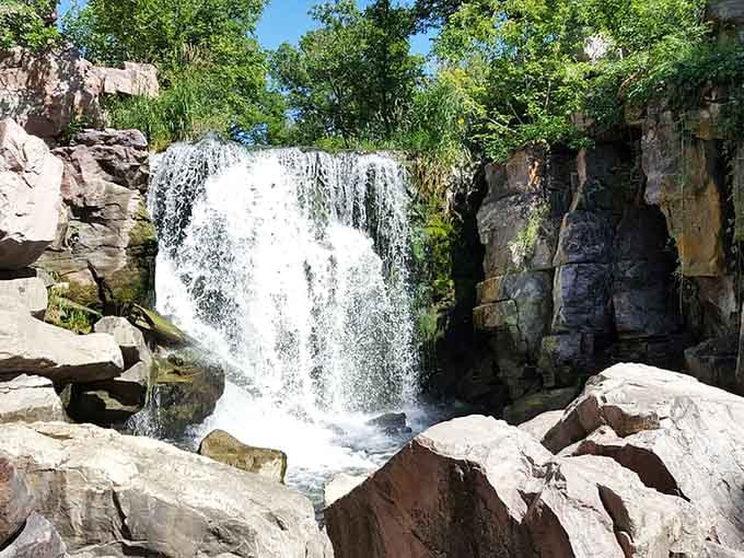 Sparkling white water cascades over ancient pink quartzite, nature showing off its billion-year-old decorating skills.