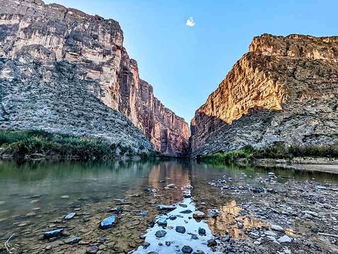 Scattered river stones and a lone wisp of moon above Big Bend's canyon walls make this feel almost impossibly peaceful.