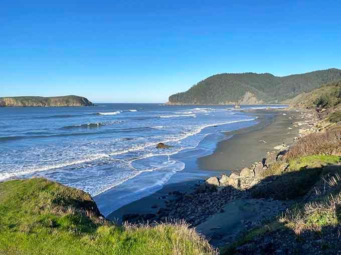 That ribbon of dark sand curving between headlands is the kind of quiet beach that makes you cancel your afternoon plans.