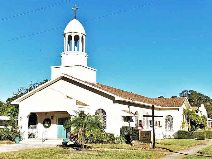 The white bell tower rises gracefully against blue skies, marking this charming church as a peaceful landmark in the community.