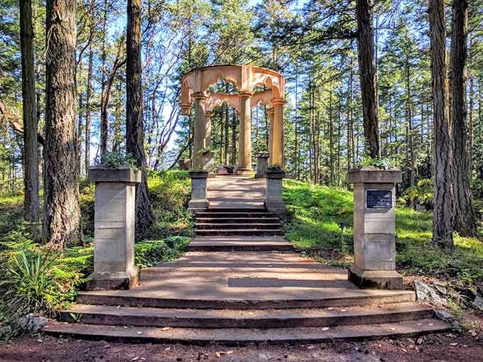 Dappled sunlight filters through the pines onto stone steps leading toward the mausoleum's arched columns, giving the whole scene a quietly magical glow.