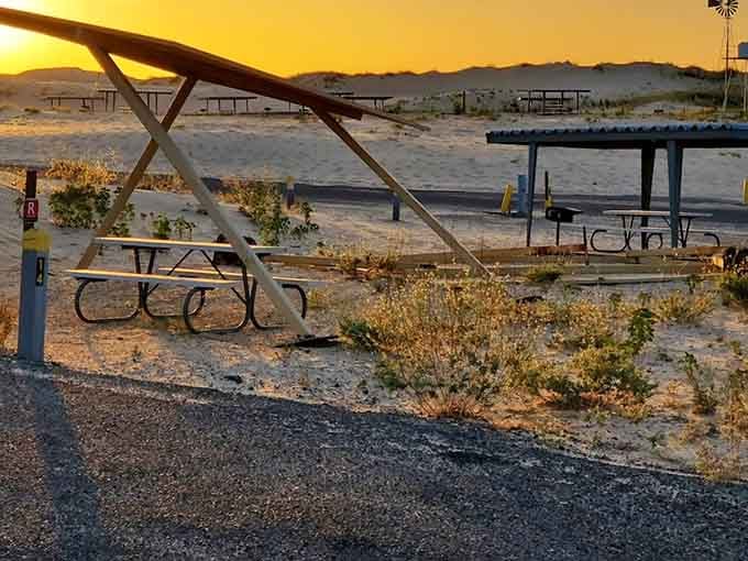 Picnic tables glow amber under a blazing desert sunset, making even an empty campsite look like a painting.