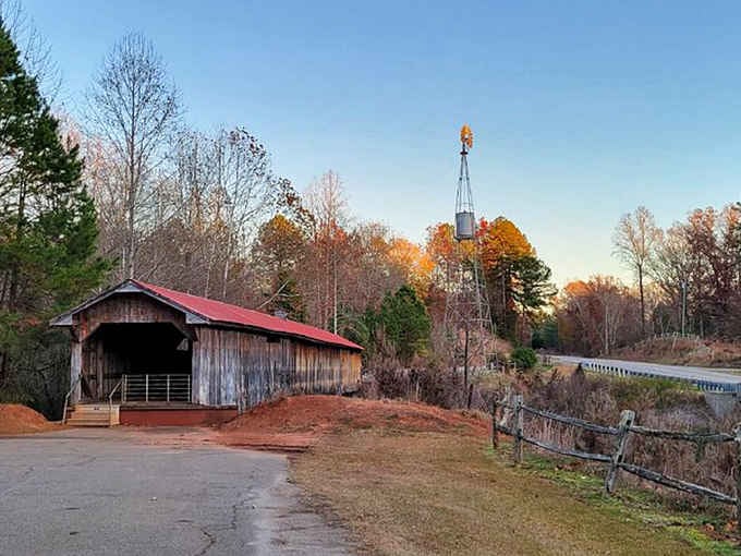 A vintage windmill stands guard nearby, giving this covered bridge the most charming co-star imaginable.
