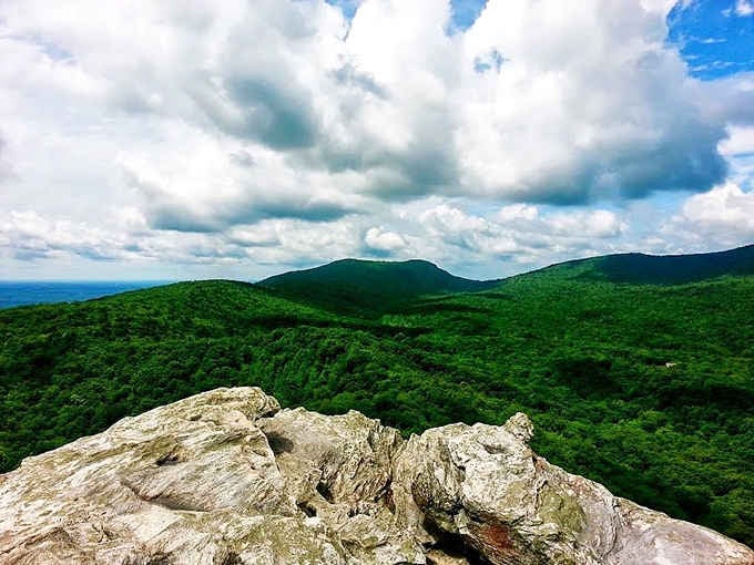 White clouds stack up dramatically behind those pale summit rocks, turning the whole sky into a free art show.