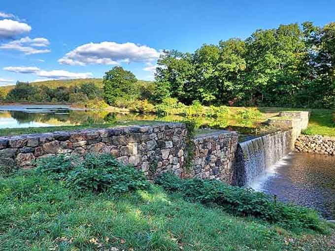 That old stone dam spilling water into the sunlit lake is the kind of scene that stops you mid-stride.