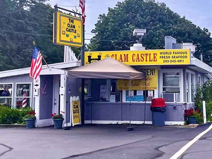 Classic seafood shack architecture meets American flags and fresh flowers, creating the perfect backdrop for legendary fried clams.