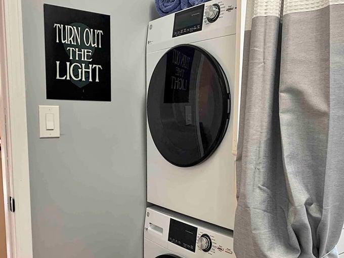 A stacked washer and dryer with a "Turn Out The Light" sign, because even laundry deserves a little drama.