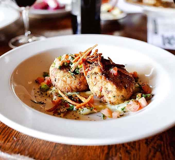 Two golden crab cakes sitting in creole aioli, topped just right. Life-changing is not an overstatement here.