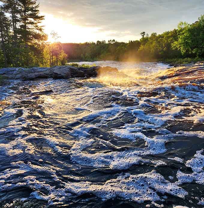The morning sun glistens off the churning river, creating a magical golden glow over the peaceful Big Falls Campground waters.