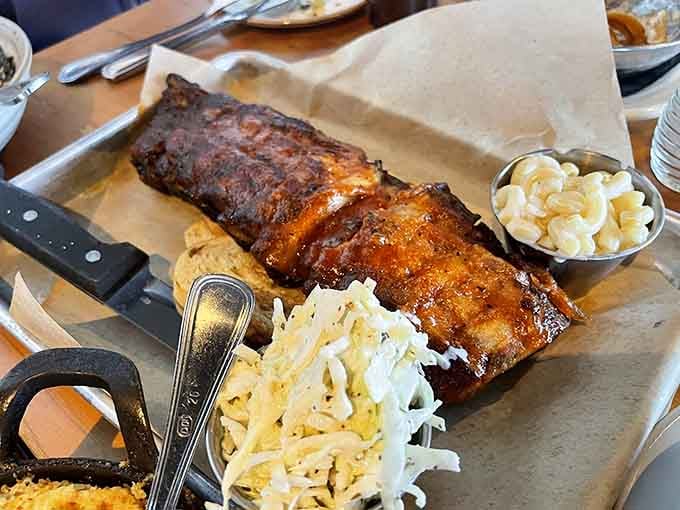Baby back ribs arrive glistening with house BBQ sauce alongside coleslaw and mac and cheese perfection.