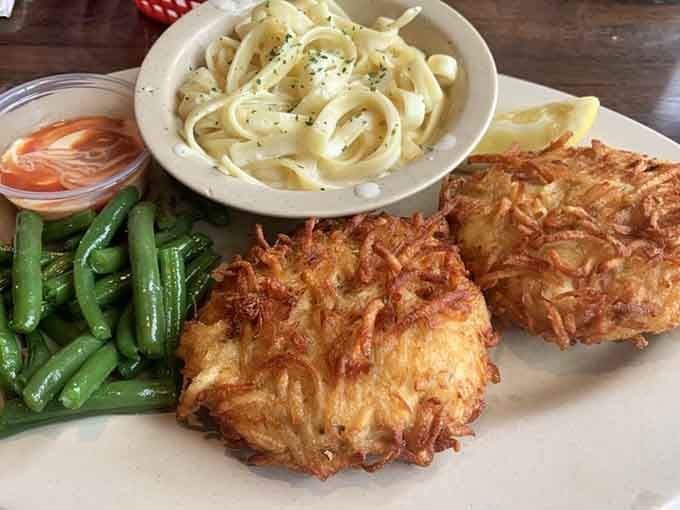 Two golden, crispy crab cakes sitting next to pasta and green beans. This plate is the reason you drove to Wheeling.