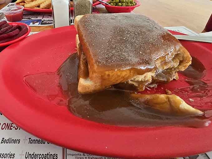Hot roast beef drowning in brown gravy on a red plate. This sandwich doesn't apologize to anyone, and it shouldn't.