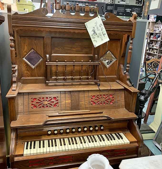 A vintage pump organ with ornate woodwork and red fretwork panels, proof that even instruments once dressed for the occasion.