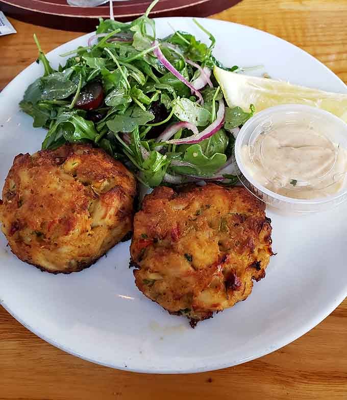 Two golden crab cakes, remoulade on the side, fresh greens nearby. This plate is the reason you made the trip to Brooklyn.