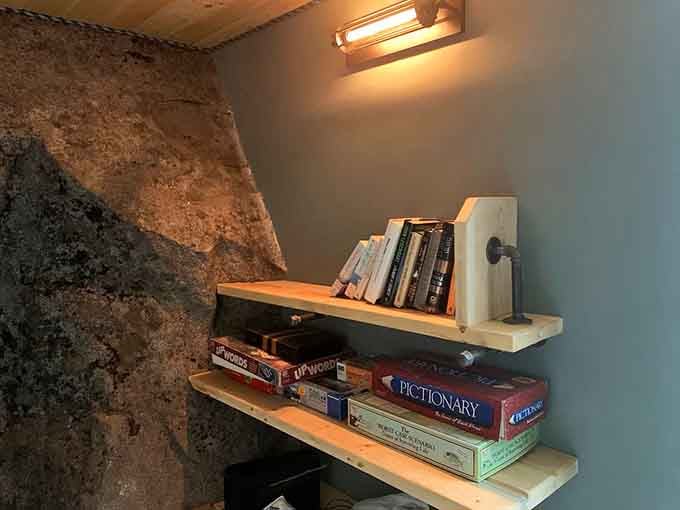 Board games and books nestle against raw stone, because even cavemen appreciated a good shelf system.