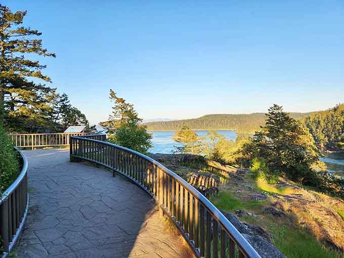 Follow this peaceful stone pathway to a scenic railed overlook, offering sunlit views of lush, forested islands.