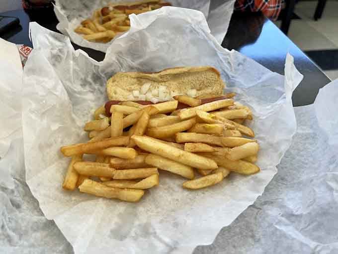 Golden fries tumbling over a classic Chicago dog, wrapped in wax paper like the greatest gift you never knew you needed.