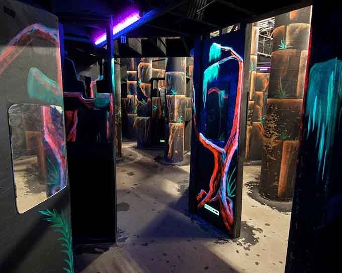 Black light, painted barriers, and glowing murals, stepping into this laser tag arena feels like walking straight into another dimension.