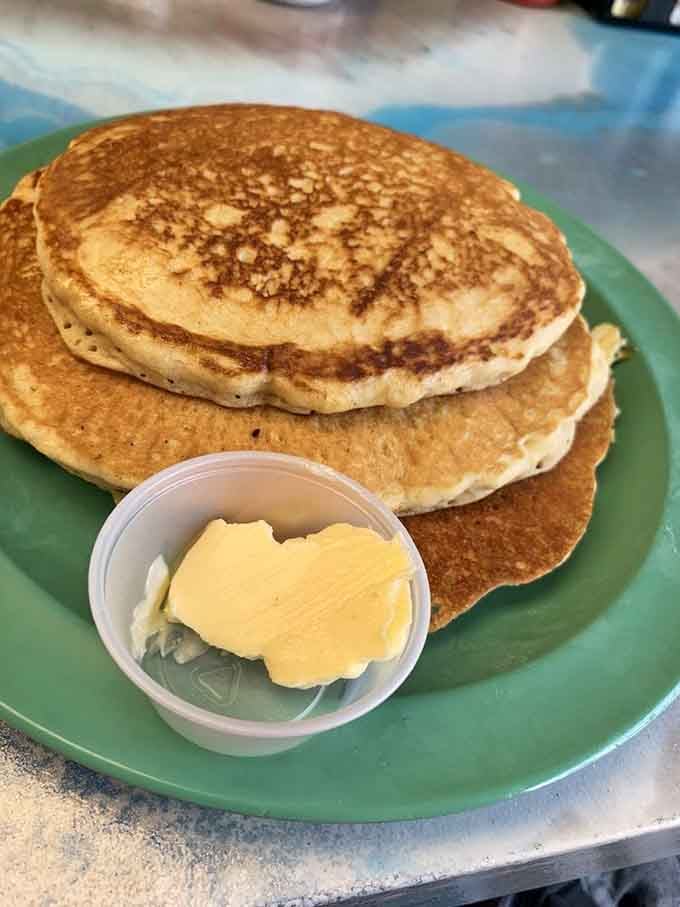 A stack of golden pancakes with butter on the side, proof that some mornings deserve a standing ovation.