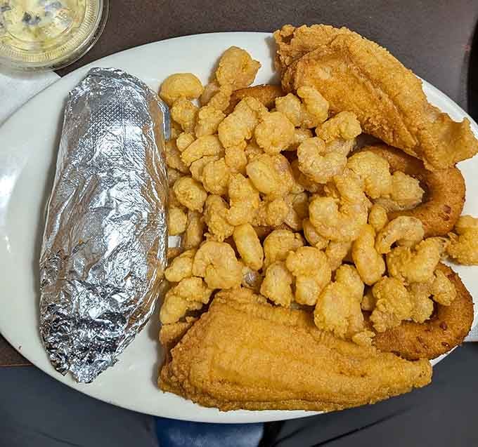 Fried catfish strips, popcorn shrimp, and a foil-wrapped baked potato. This plate means serious, no-apologies business.