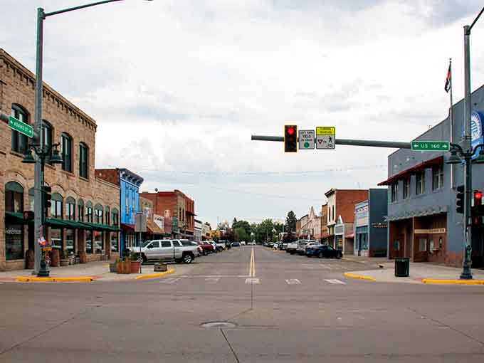Main Street stretching wide under a cloudy Colorado sky, lined with brick storefronts that have seen a century of good stories.