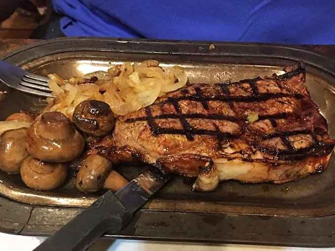 A ribeye with grilled mushrooms and onions that looks like it was painted by someone who truly loves you.