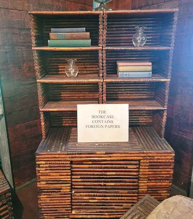 A bookcase built from foreign newspapers holding actual books. The irony here is genuinely delightful and nobody can convince us otherwise.