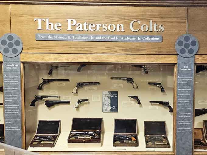 Samuel Colt's revolvers, born right here in Paterson, lined up behind glass like the most consequential New Jersey invention ever.