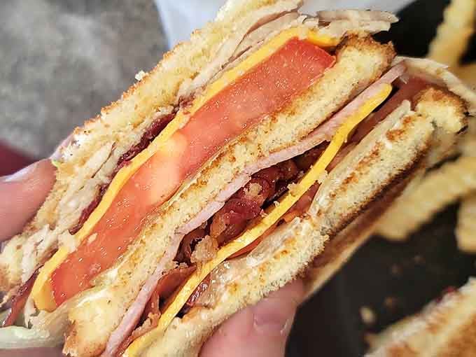 Layers of ham, turkey, bacon, and tomato stacked high. This club sandwich means serious, delicious business.