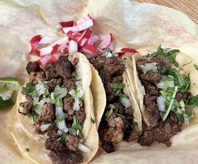 Three asada tacos topped with fresh cilantro and onion, the kind of simple perfection that makes you question every meal you've eaten before.