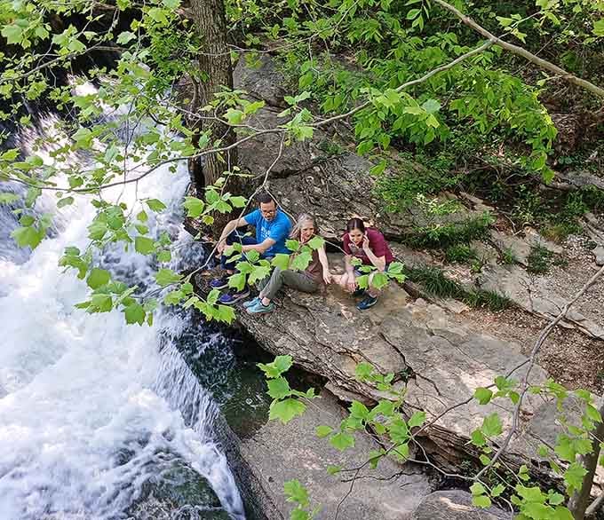 Friends perched on rocks beside rushing water, proof that the best seats in Indiana require no reservation.